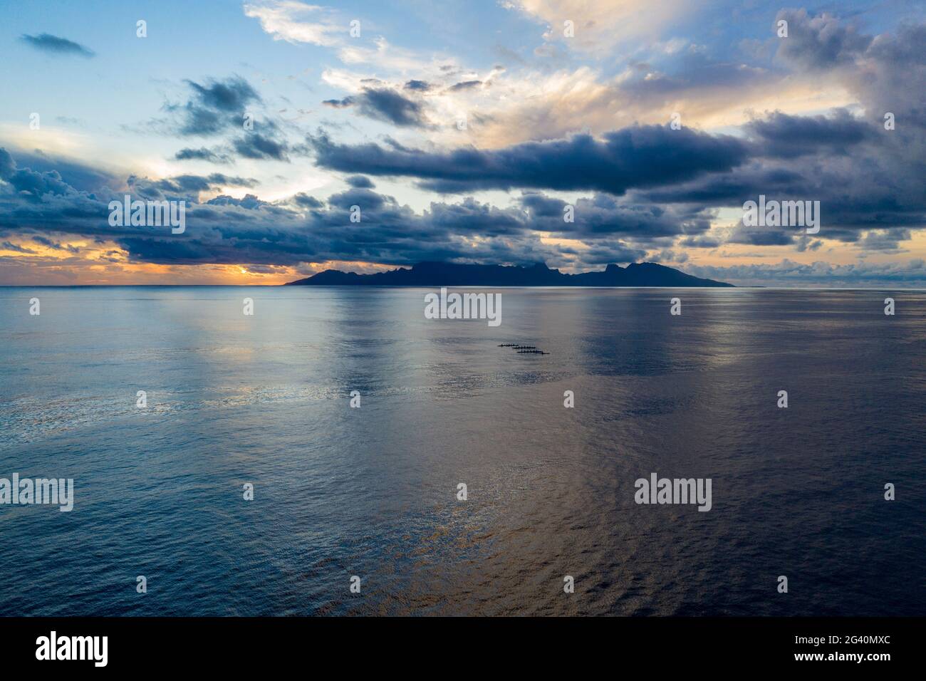 Aerial view of outrigger racing canoes at sunset with Moorea Island in ...