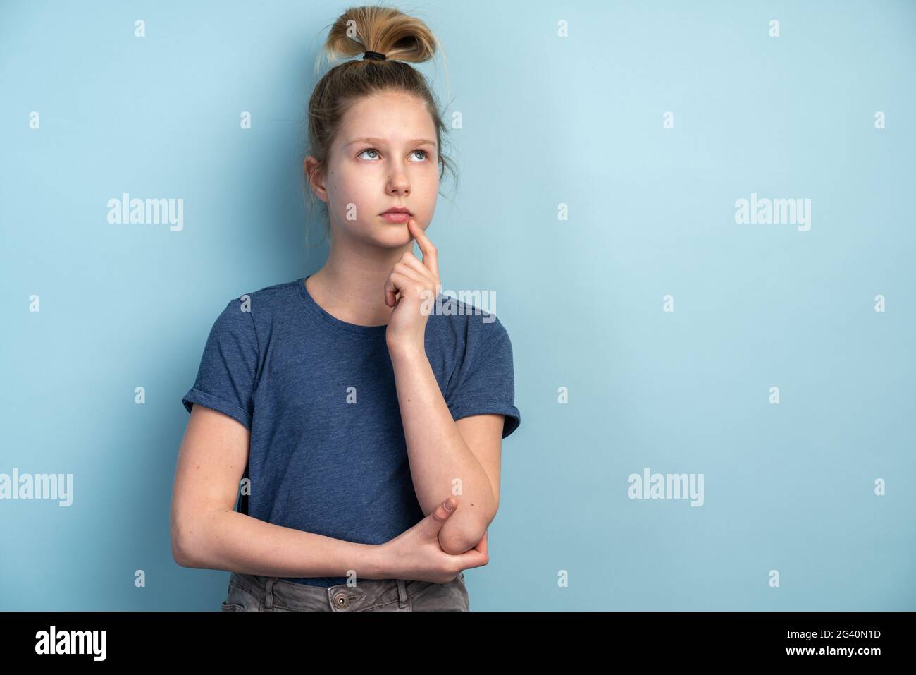Cute teen girl thinking about something on blue wall background. Girl ...