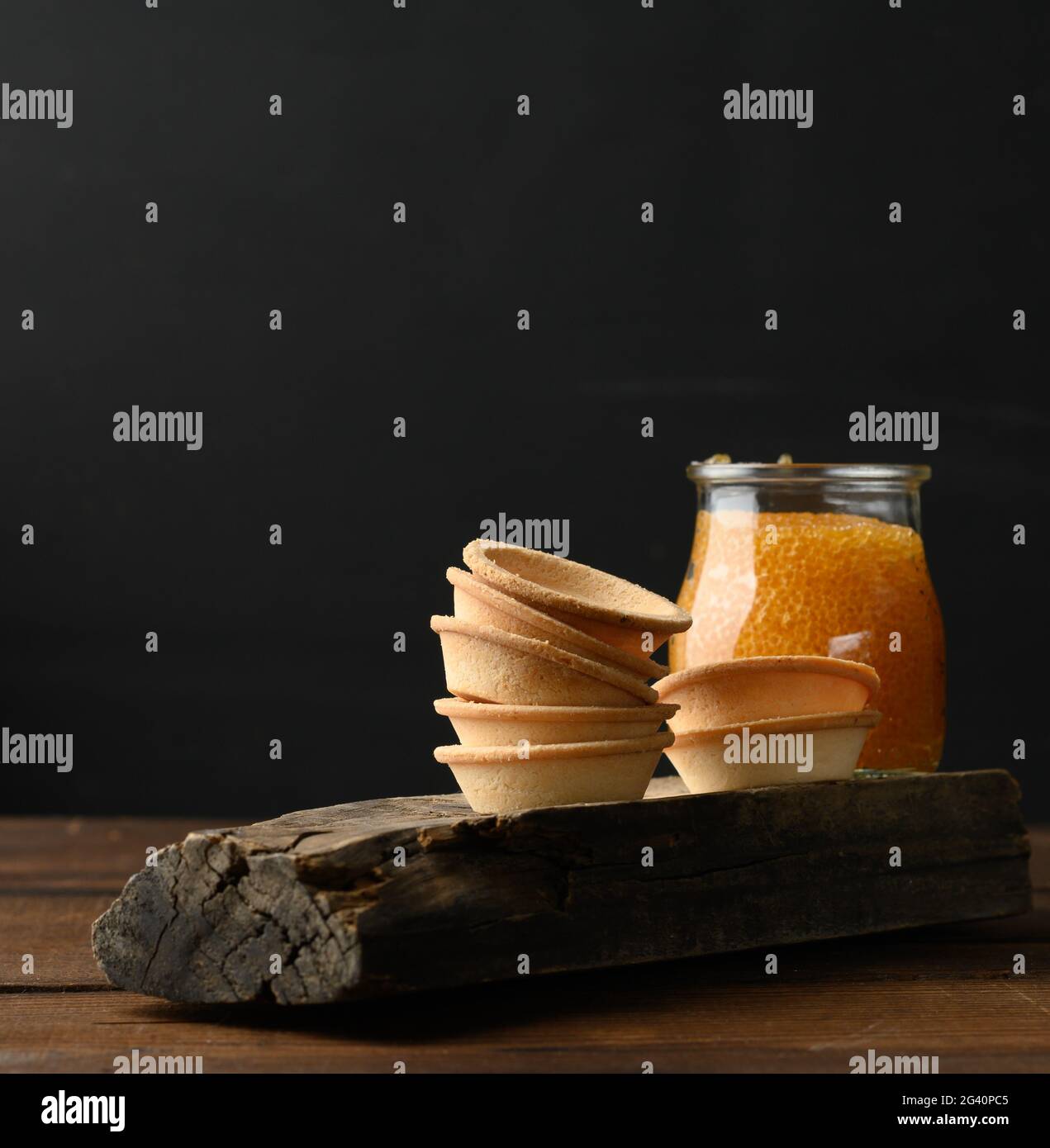Pike caviar in a glass jar and round tartlets on a black background ...