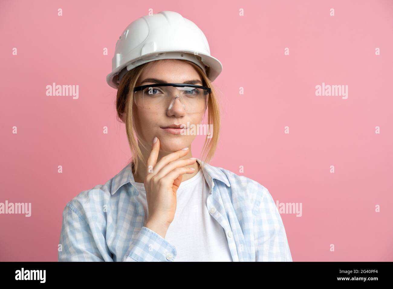 Pretty girl - an engineer in a construction helmet and glasses touches ...