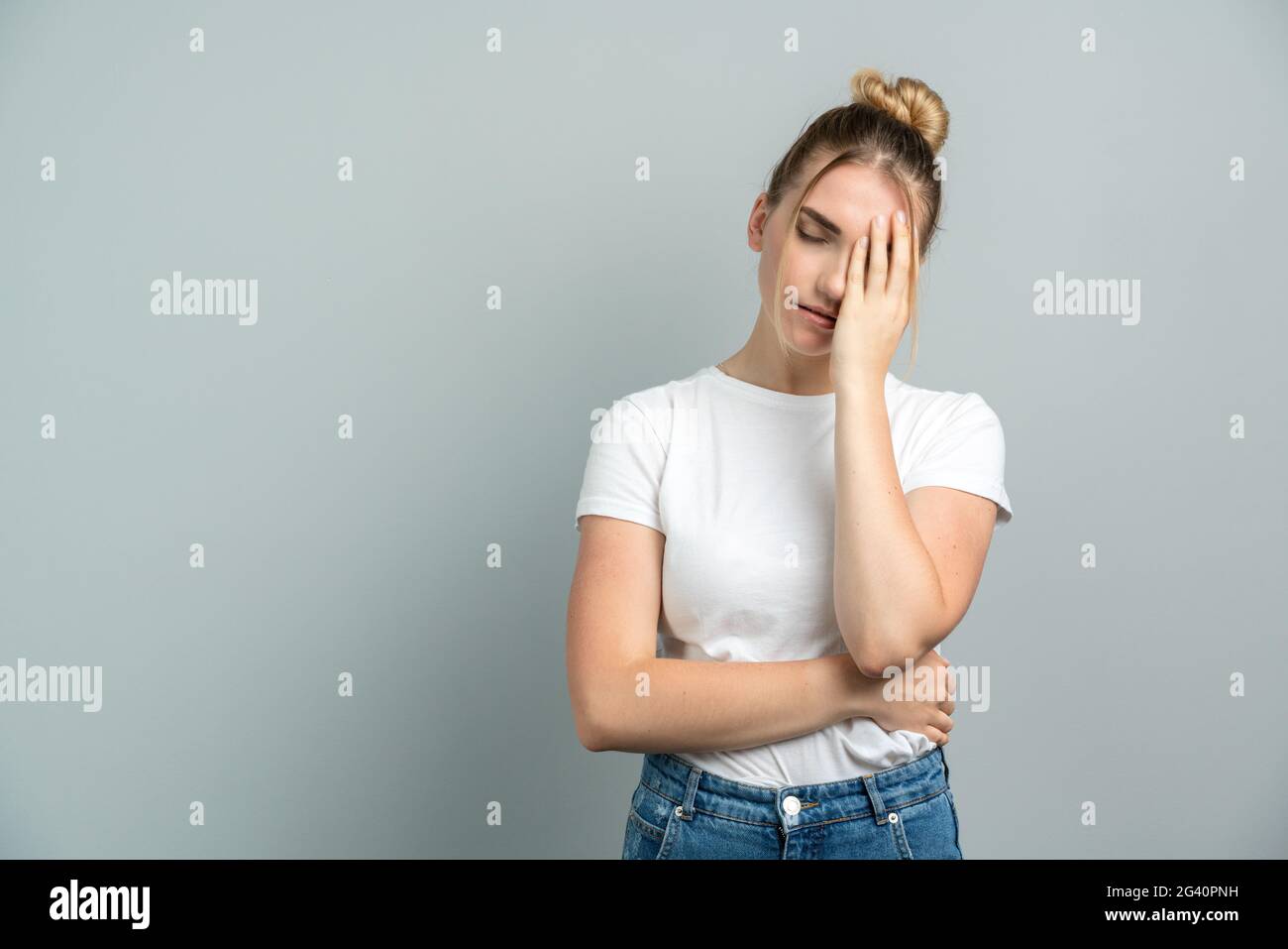 Young adult girl posing with a raised look, holding a hand on his face ...