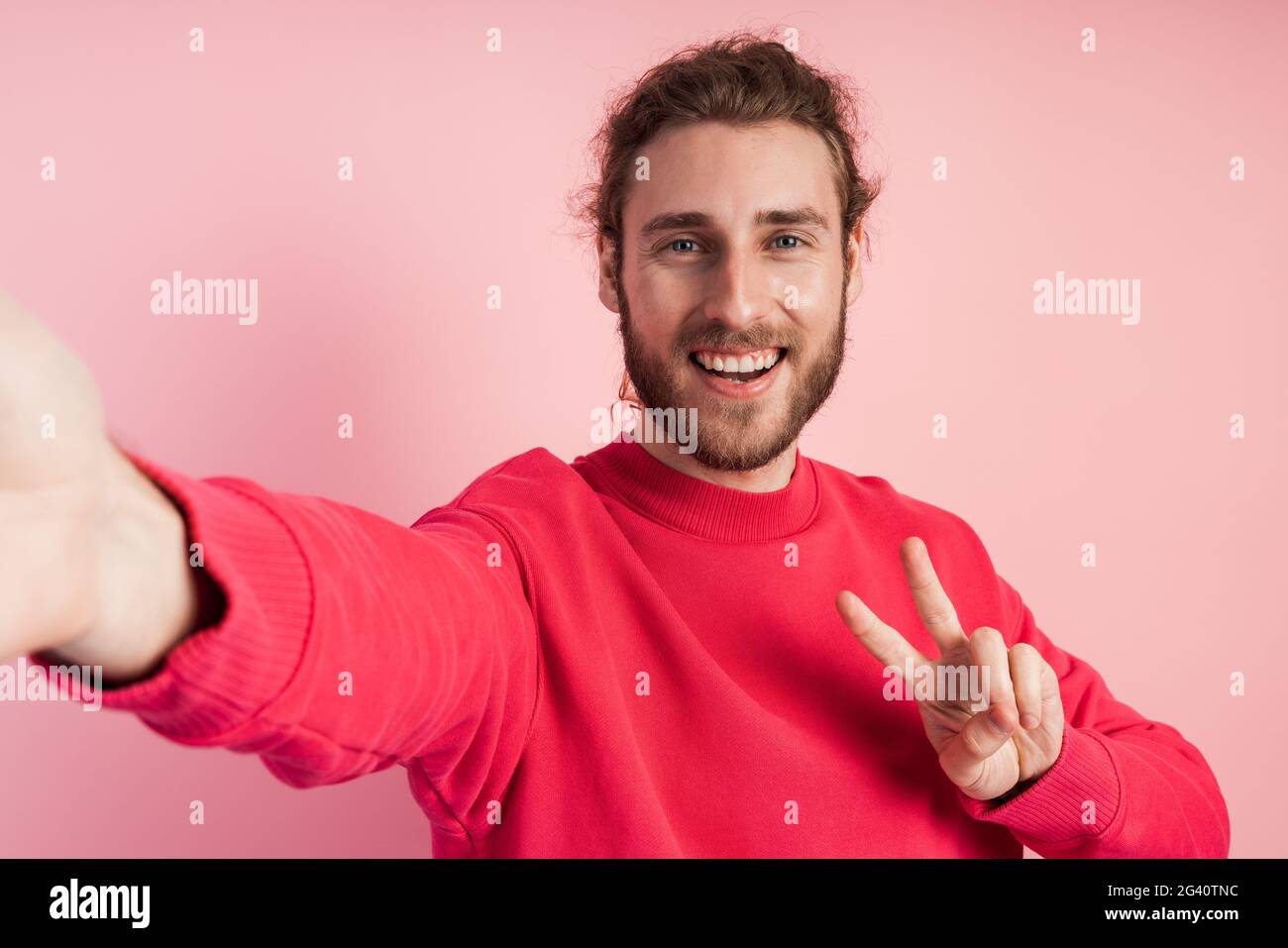 Attractive, good man takes a selfie and shows a sign of victory ...