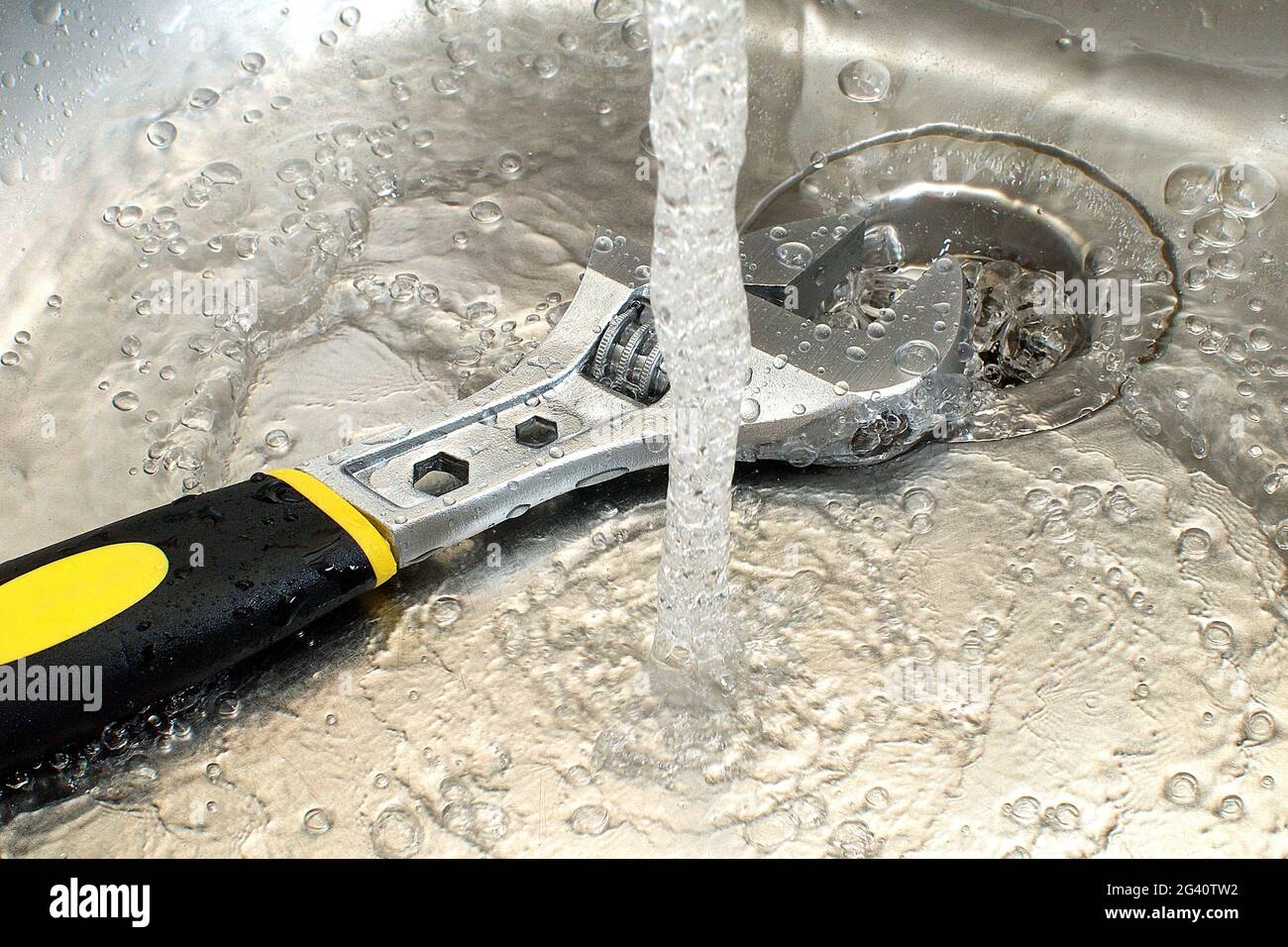 plumbing tool adjustable wrench in a sink under pouring water, closeup ...