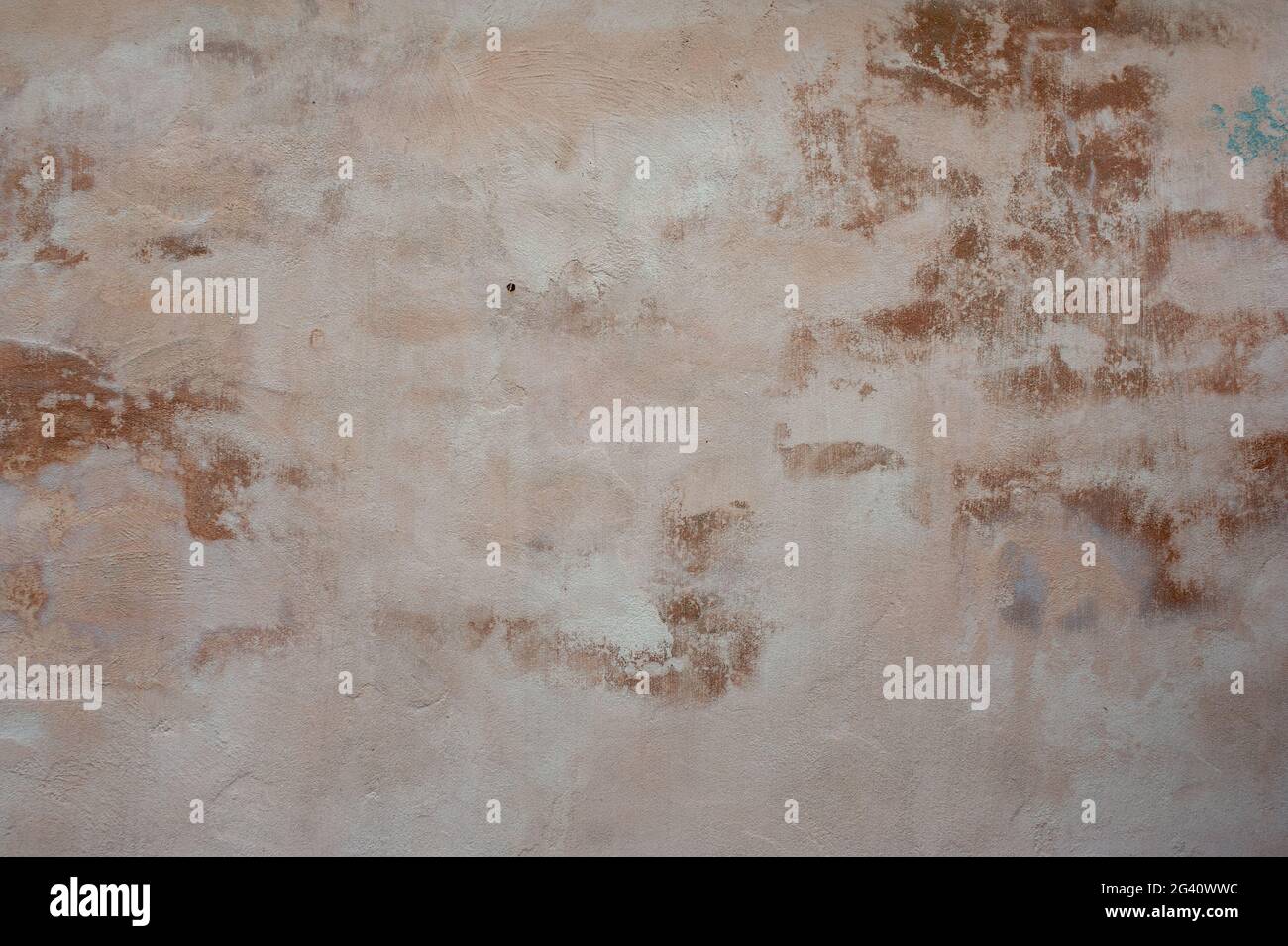 An old wall with a bright faded orange color and a bit of fallen ...