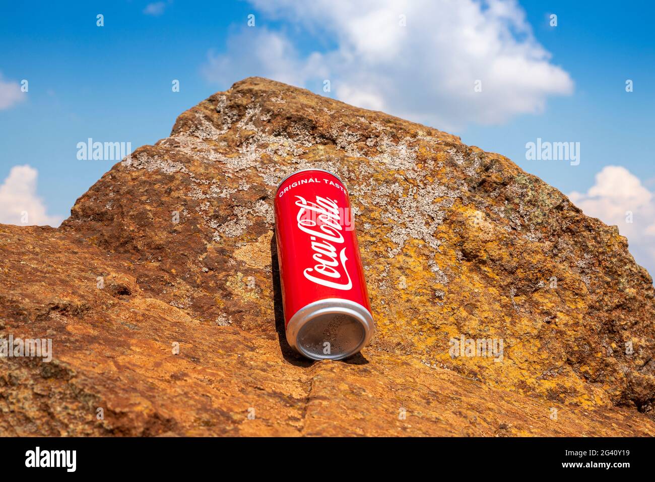 Coca-cola can resting on the rock against blue sky. Illustrative ...