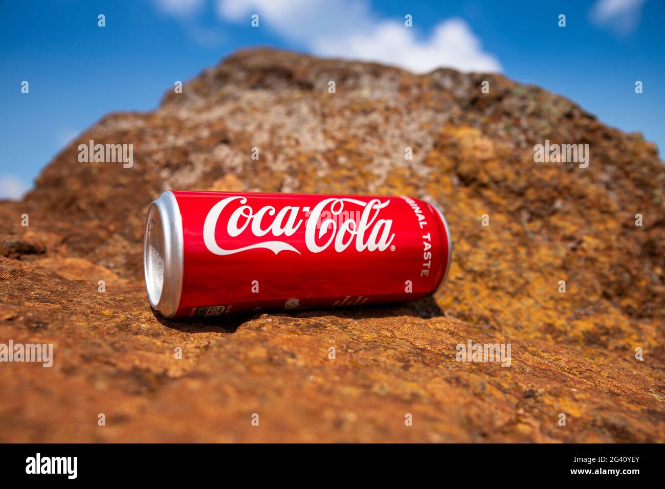 Coca-cola can resting on the rock against blue sky. Illustrative ...