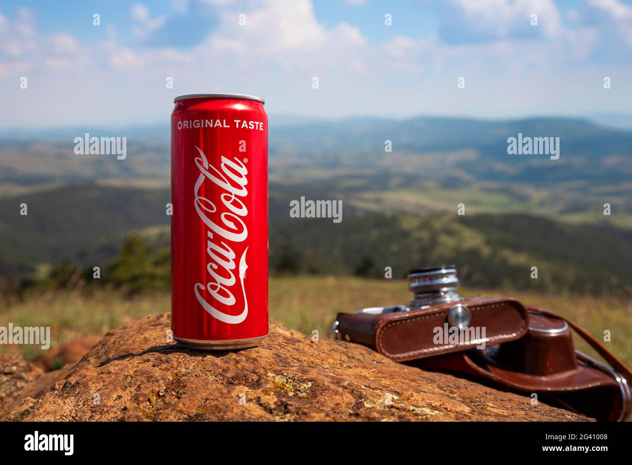 Coca-cola can and vintage photo camera resting on the rock at the top ...