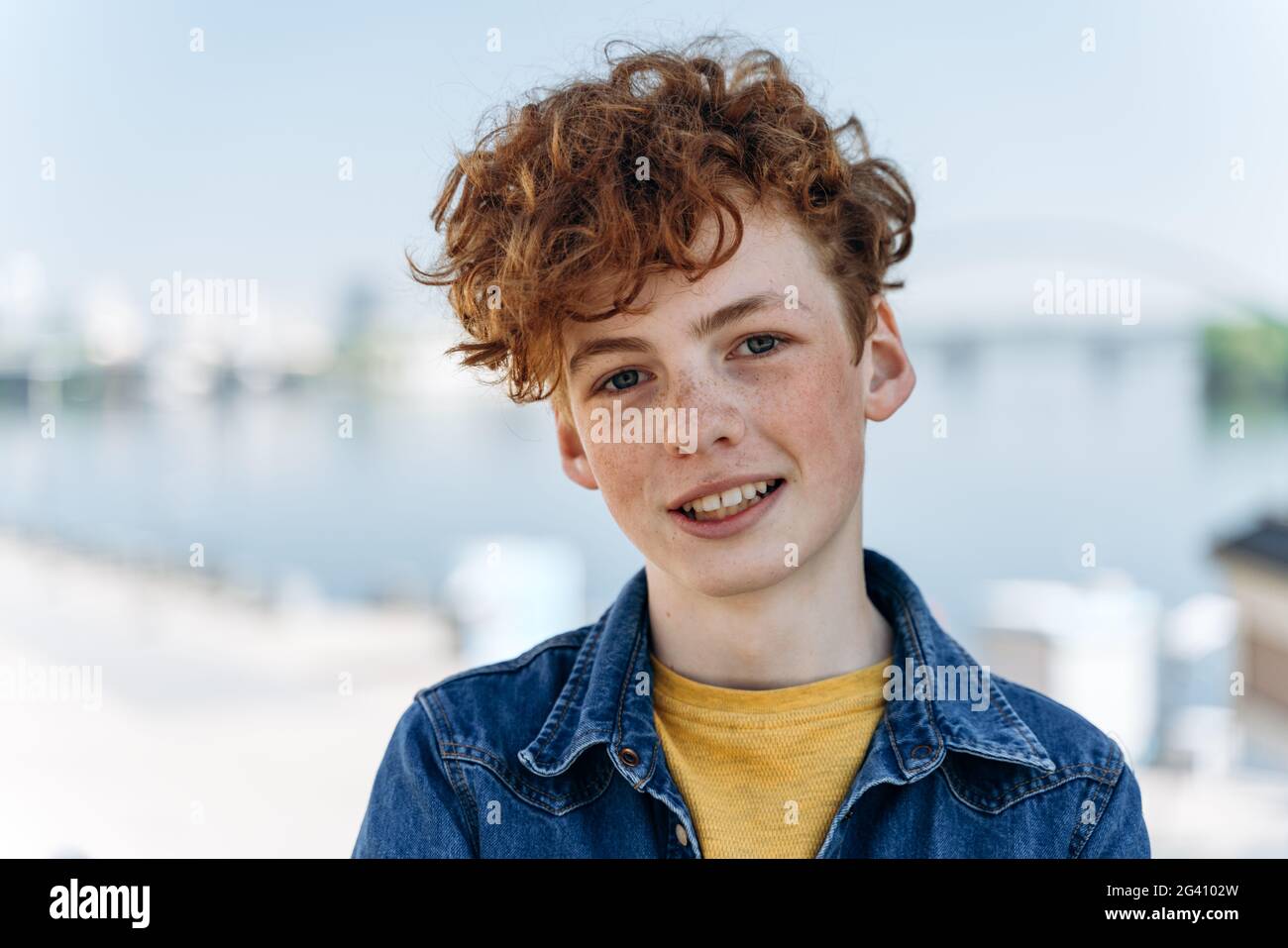 Handsome, smiling boy with red hair posing against the backdrop of the ...