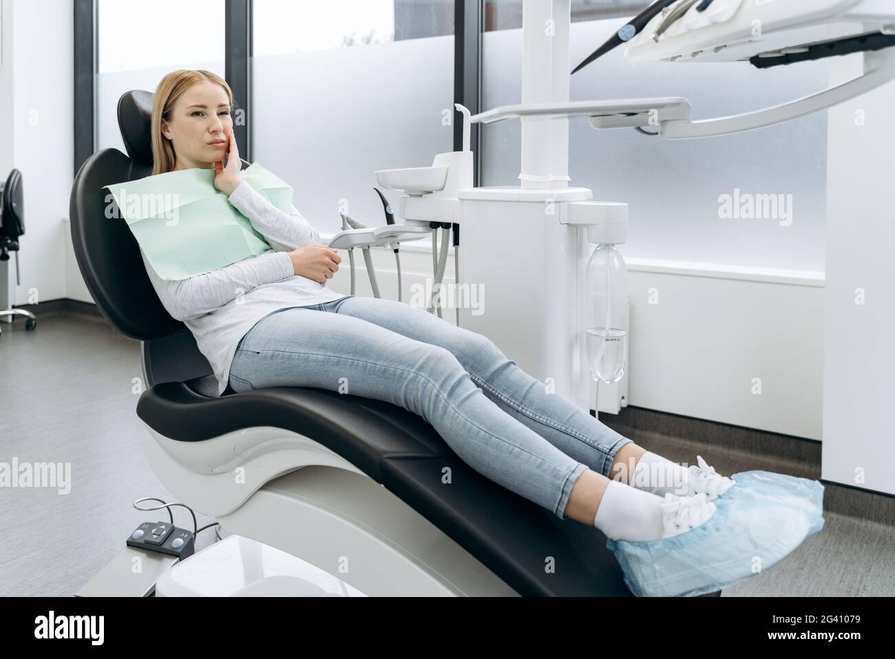 Cute, crooked woman touches sitting in a dental chair. The woman ...