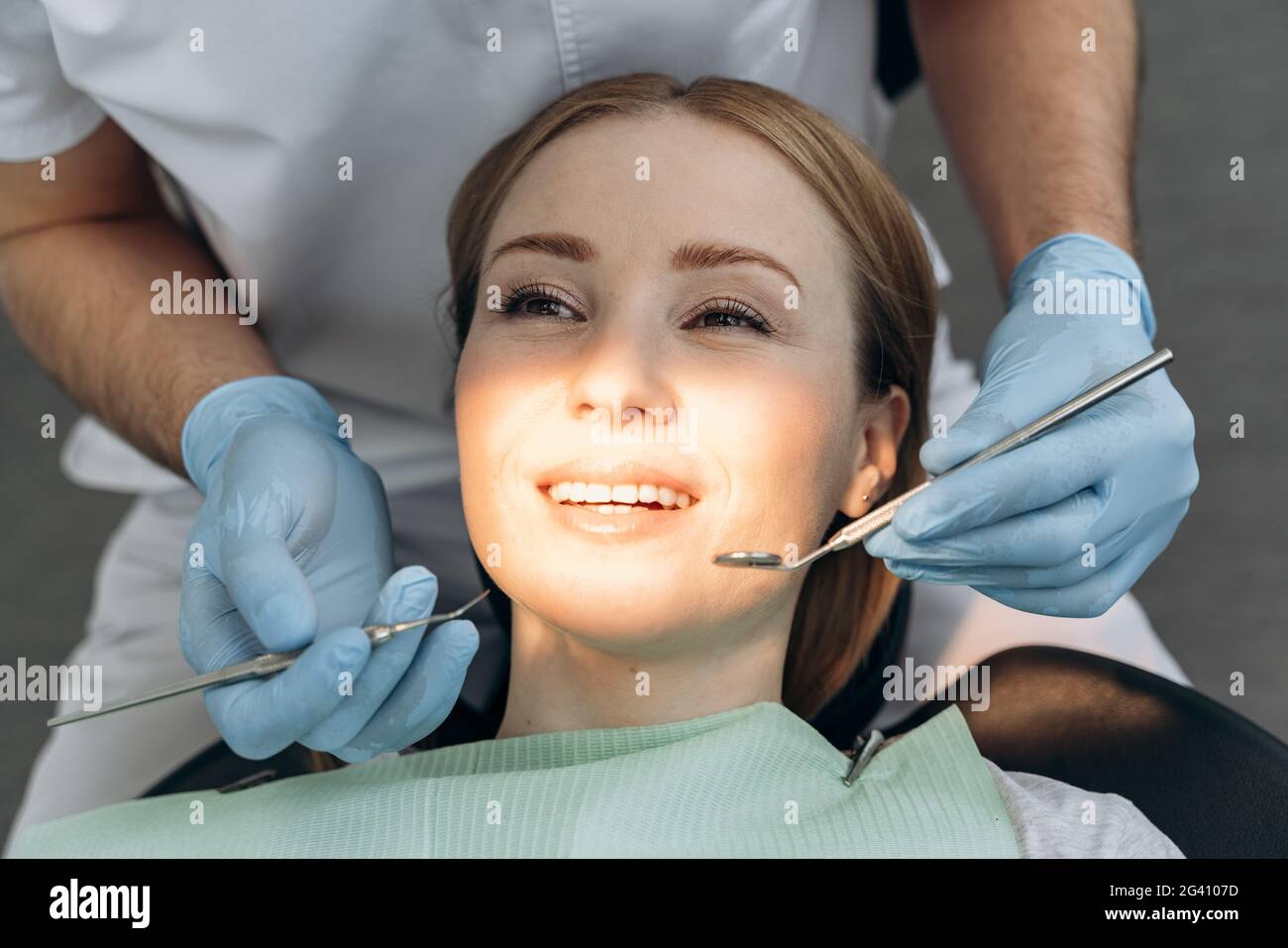 Positive, smiling woman in a dental chair. Dentist holding dental tools ...