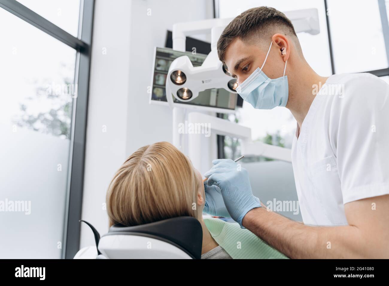Rear view, a dentist examines the teeth of an attractive woman. Dental ...