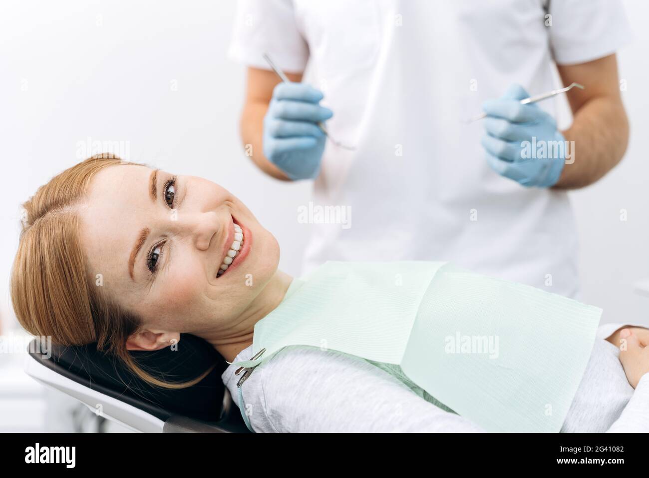 Charming woman sitting in a dental chair, looking at the camera. The ...