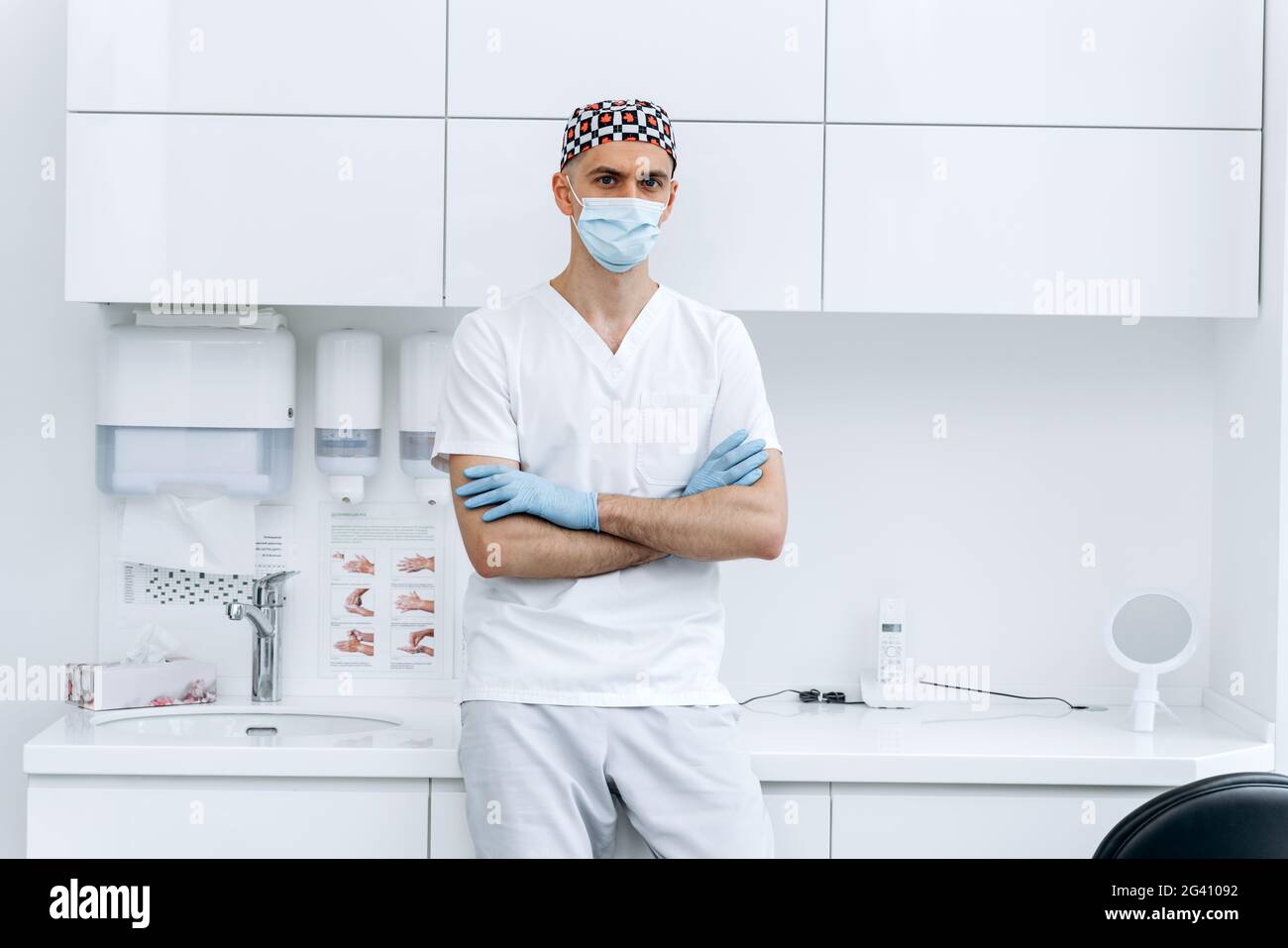 Young dentist in medical clothes in a mask and a medical cap in a ...