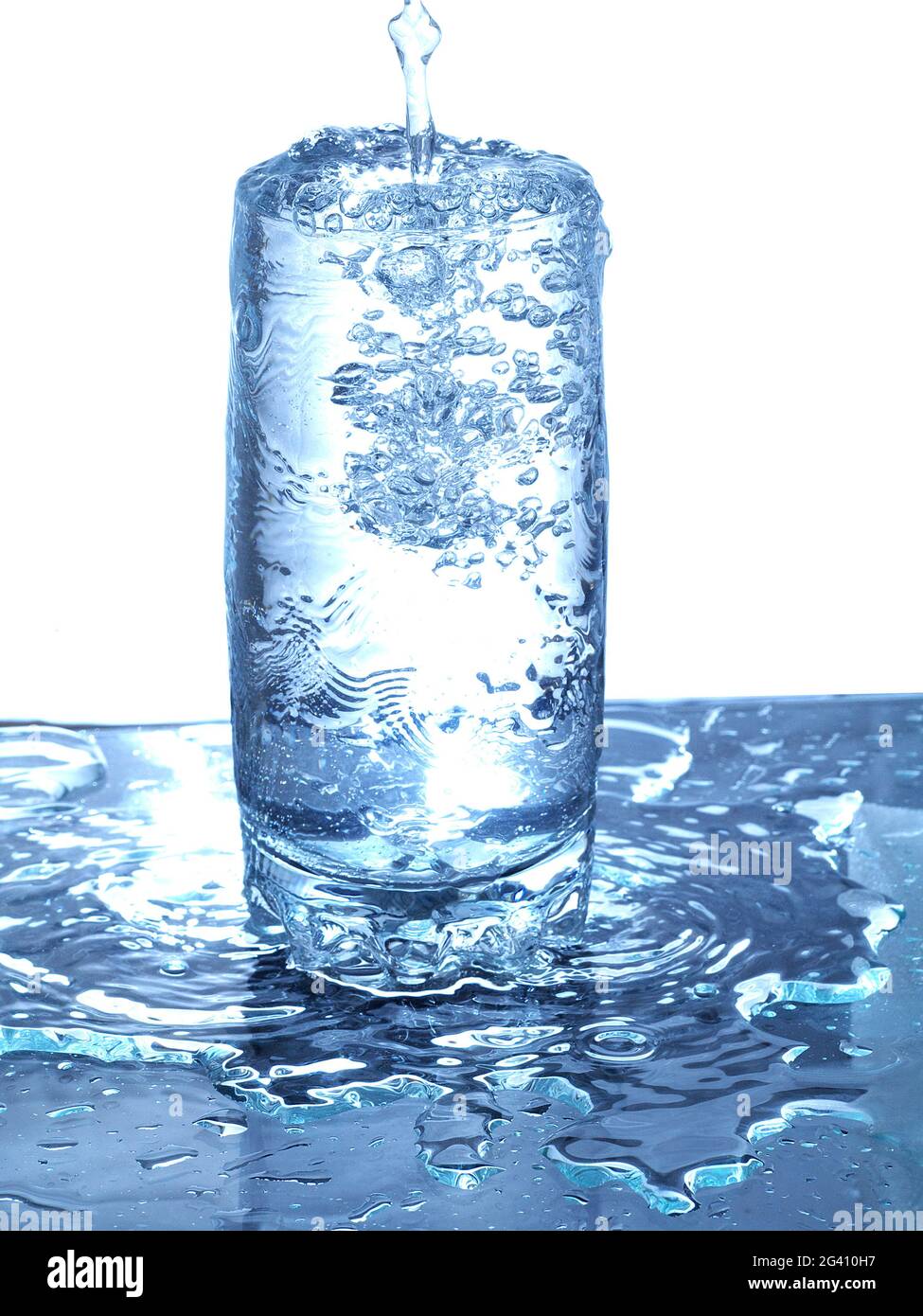 pouring water to glass with overflow Stock Photo - Alamy