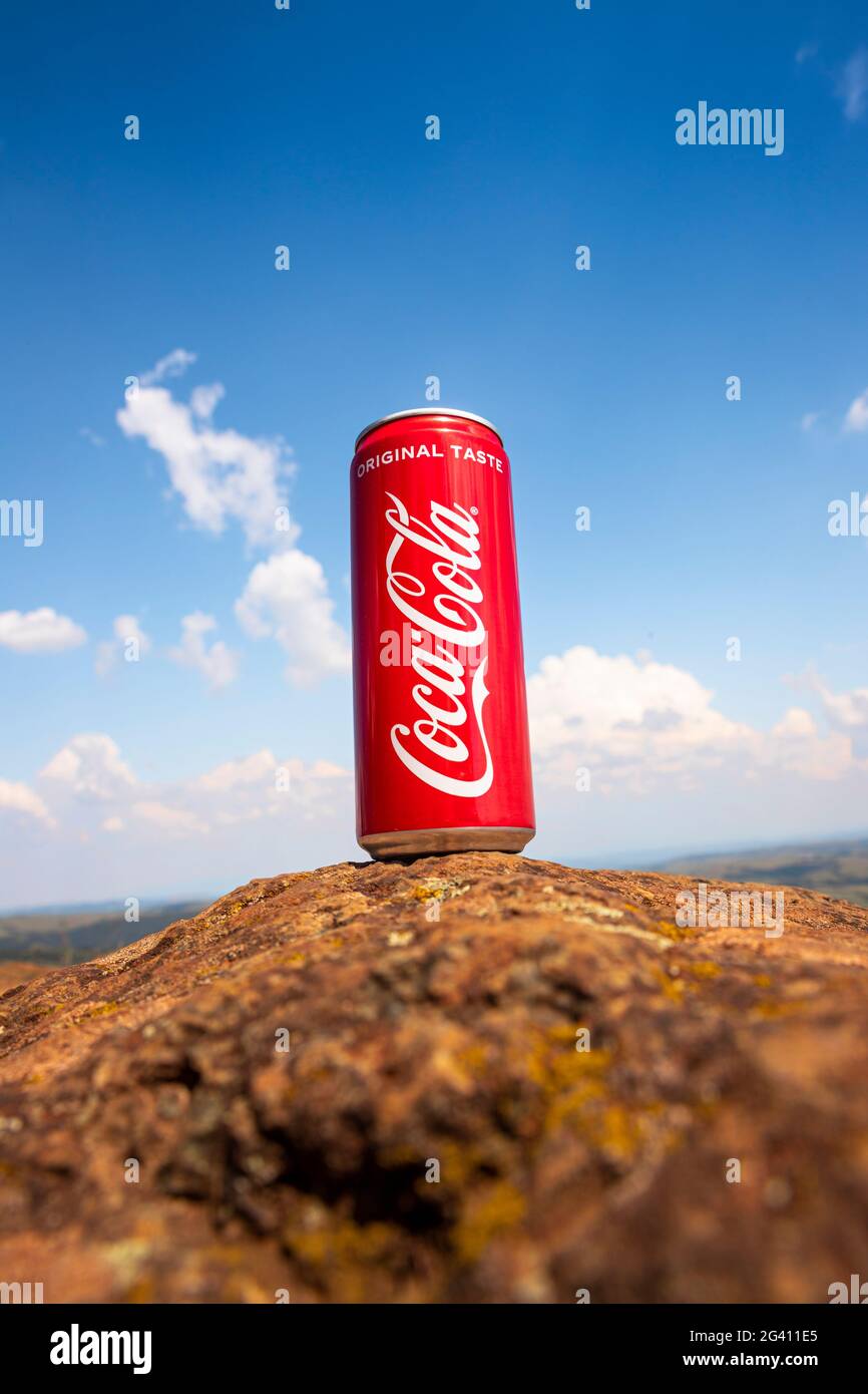 Coca-cola can resting on the rock against blue sky. Illustrative ...