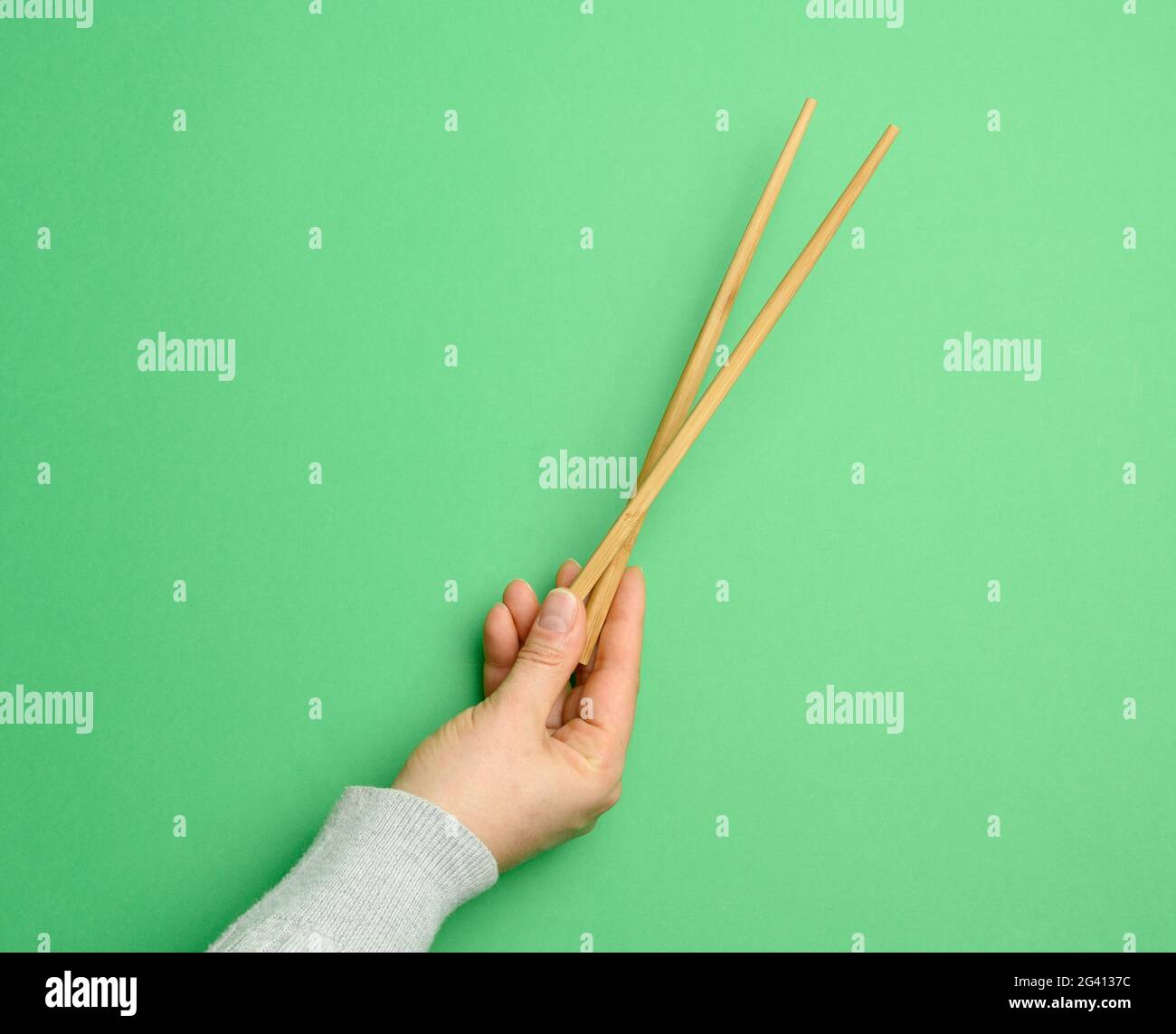 Pair of wooden chopsticks in a female hand on a green background Stock ...
