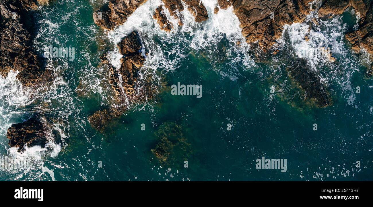 A dangerous sea wave crashes into the rocky coast with spray and foam ...