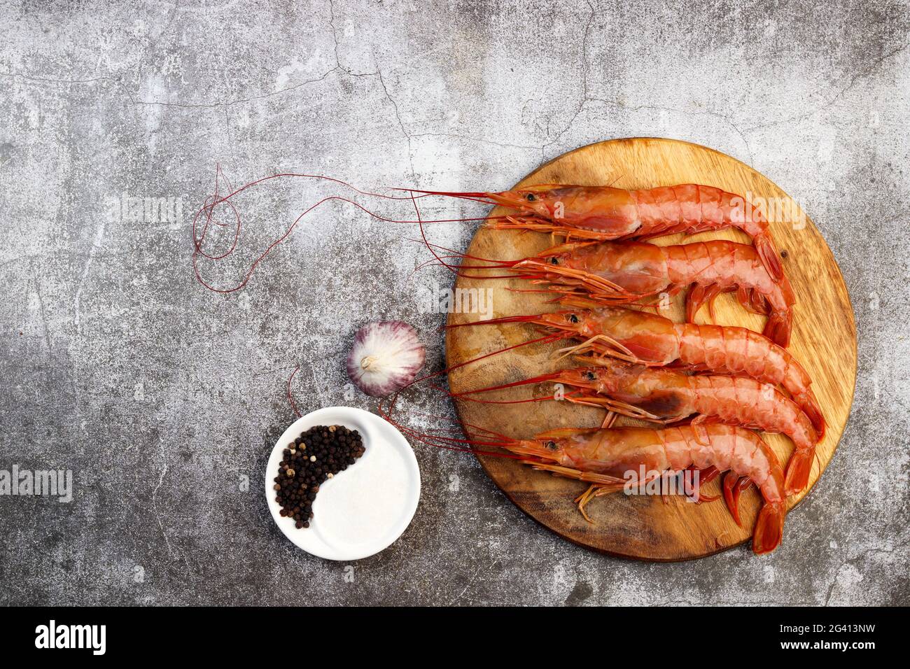 Argentinian raw red prawns (shrimps) with heads on a round wooden ...
