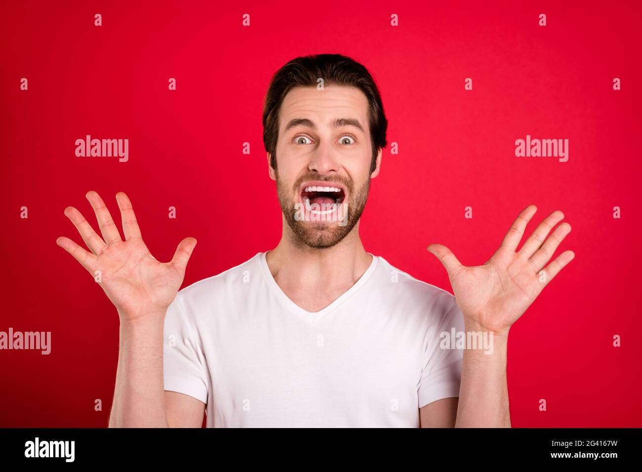 Photo of scared young brown hairdo man hands up wear white t-shirt ...