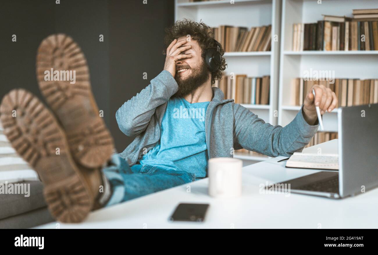Facepalm. A young programmer works remotely at home. A young man smiles ...