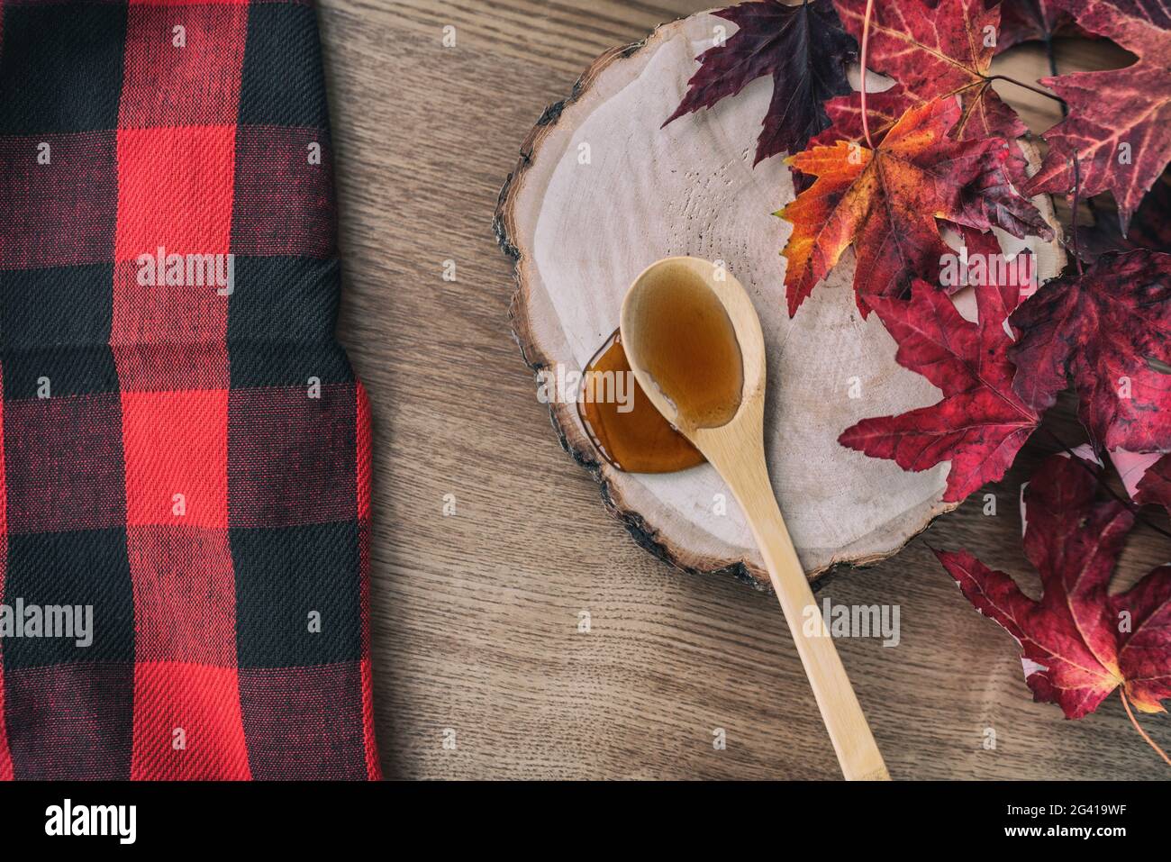 Maple syrup in wooden spoon top view over dining table wood log. Quebec ...