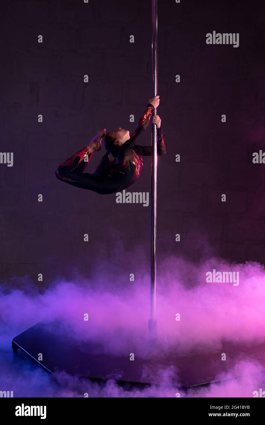 Graceful girl performing pole dance on stage with neon lights Stock Photo - Alamy