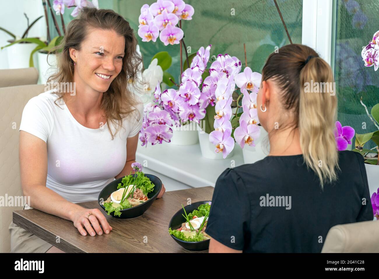 girlfriends having lunch in a restaurant vegetable salad with tuna and ...