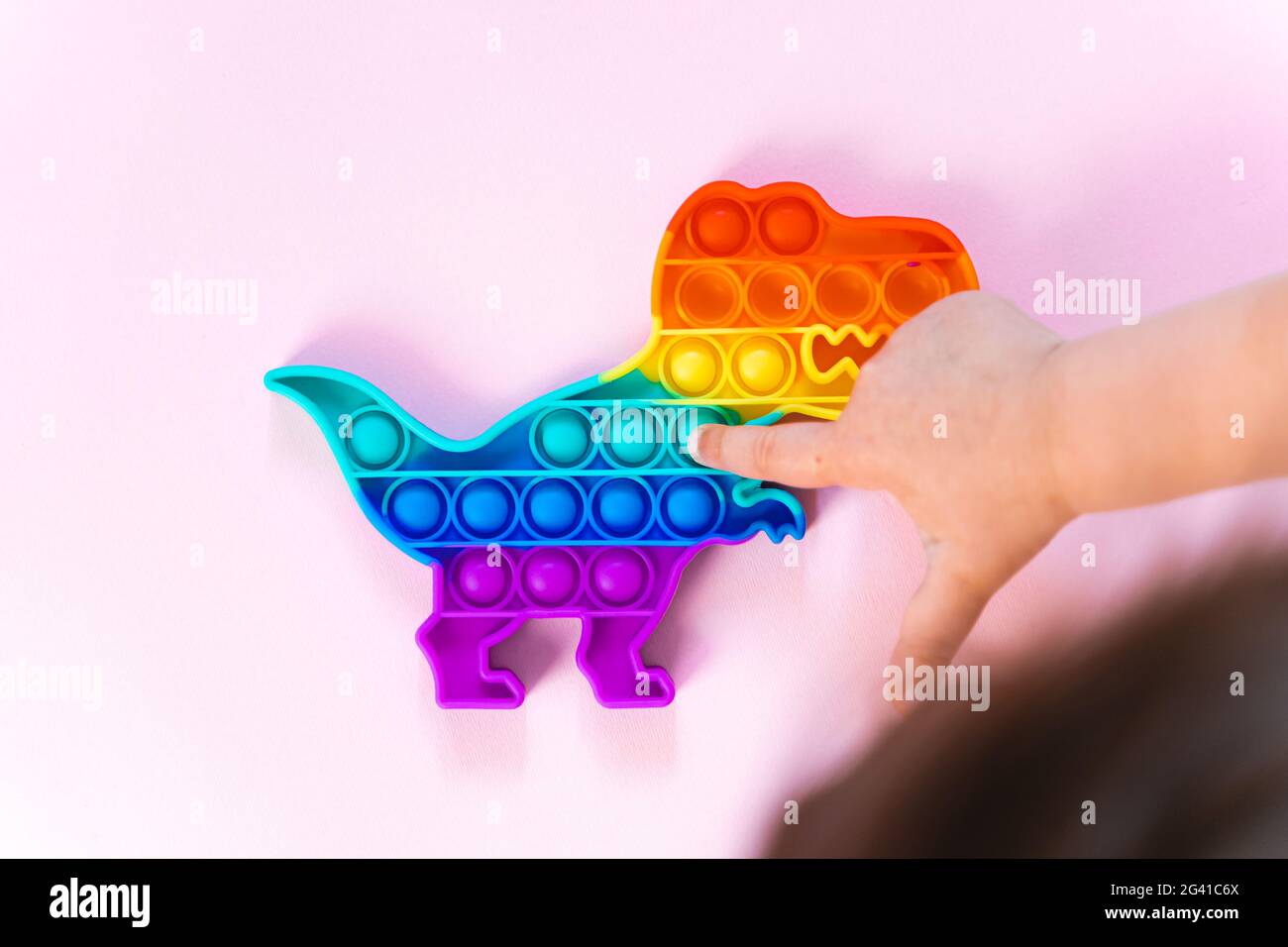 Popit rainbow toy in rainbow colours and dino shape. Trendy bubble pop ...