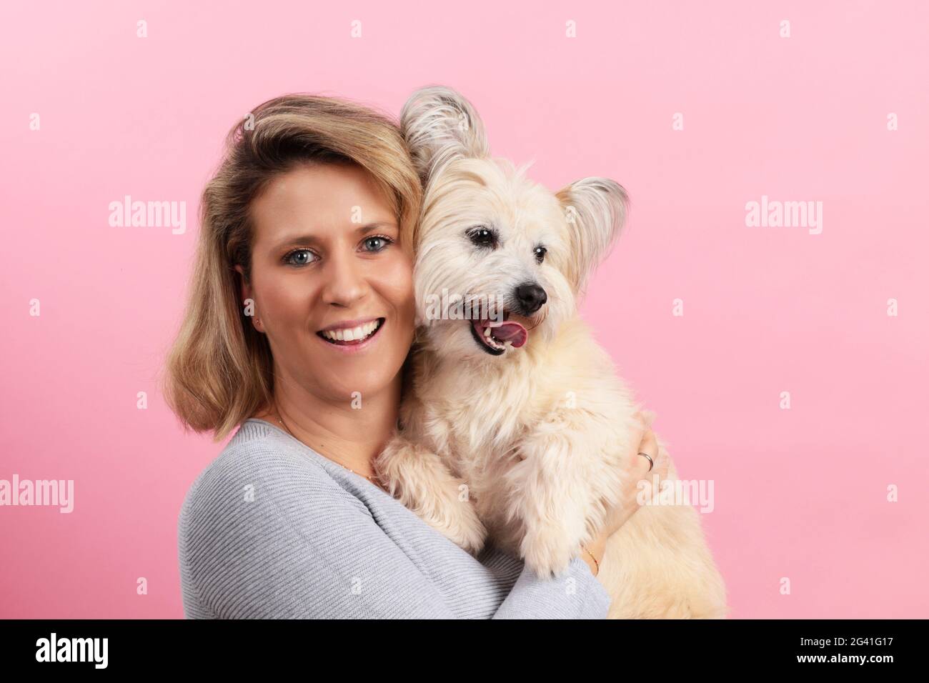 Happy woman with small dog in front of pink background Stock Photo - Alamy