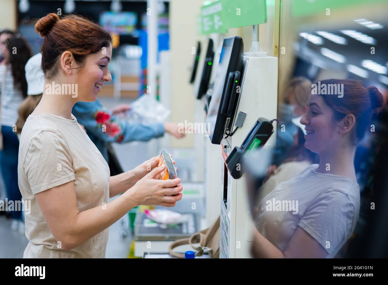 Caucasian woman uses a self-checkout counter. Self-purchase of ...