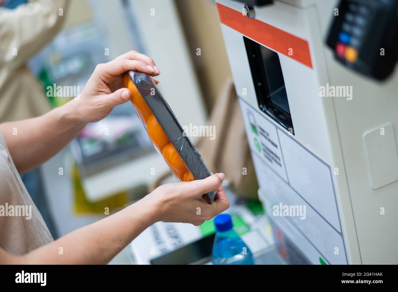 A woman scans products at a self-checkout counter. Close-up of female ...