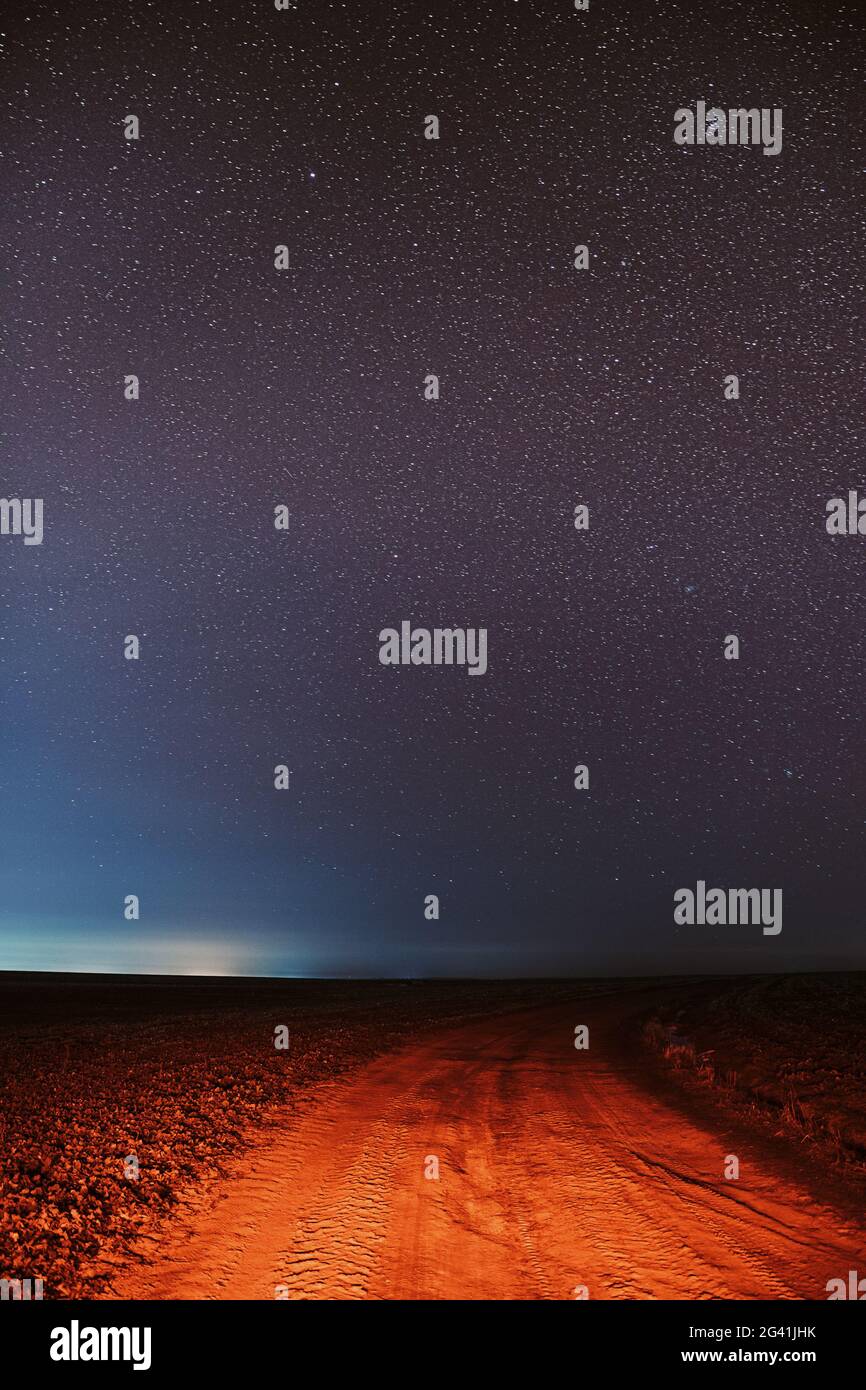 Night Starry Sky With Glowing Stars Above Country Road Is Lit In Red ...