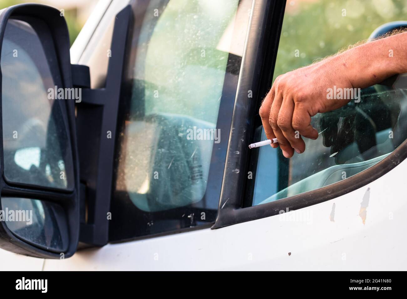 Driver holding hand on car door with open window, waiting in traffic ...