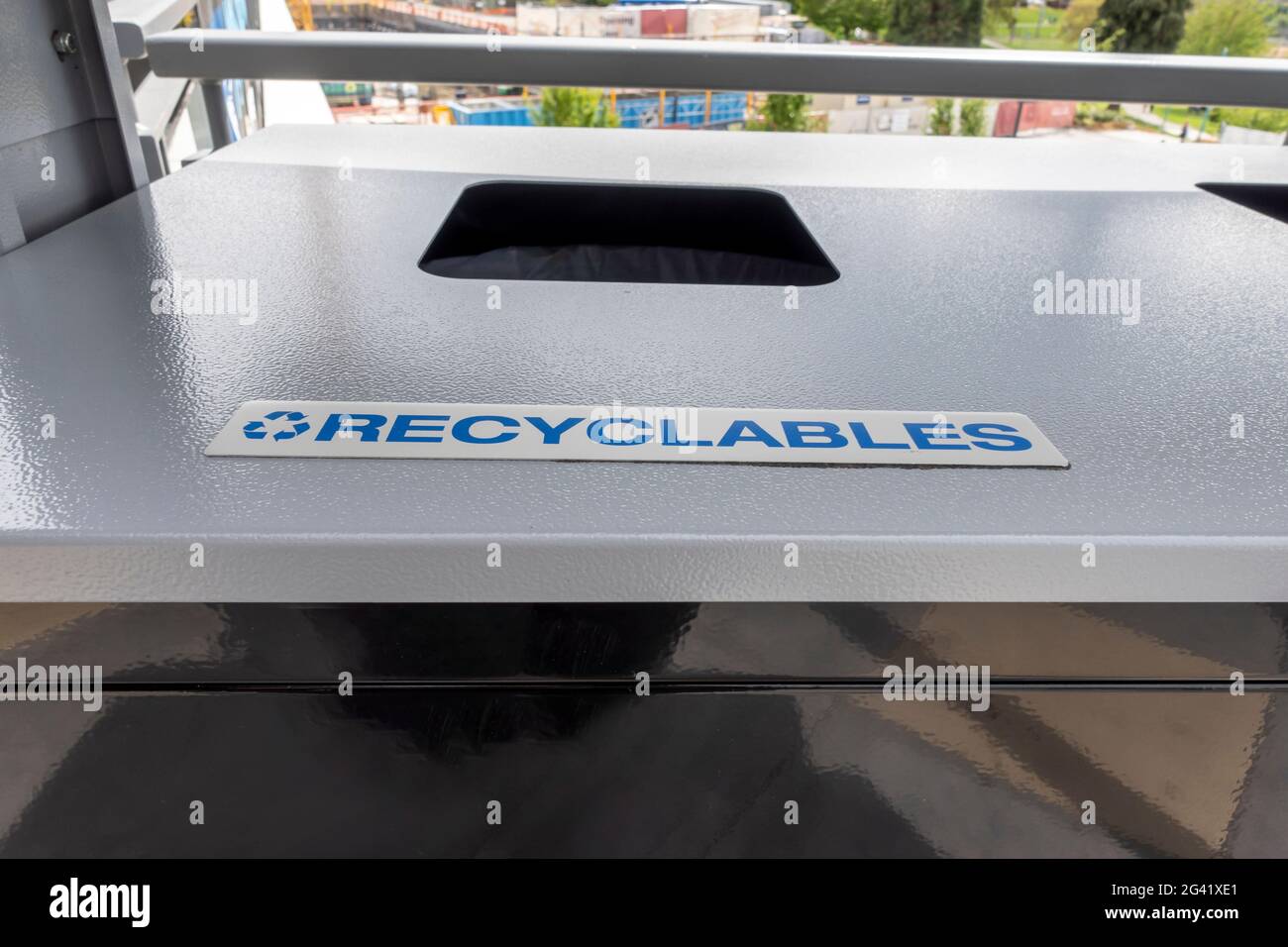 Angled view of a covered, grey and black outdoor trash bin labelled for ...