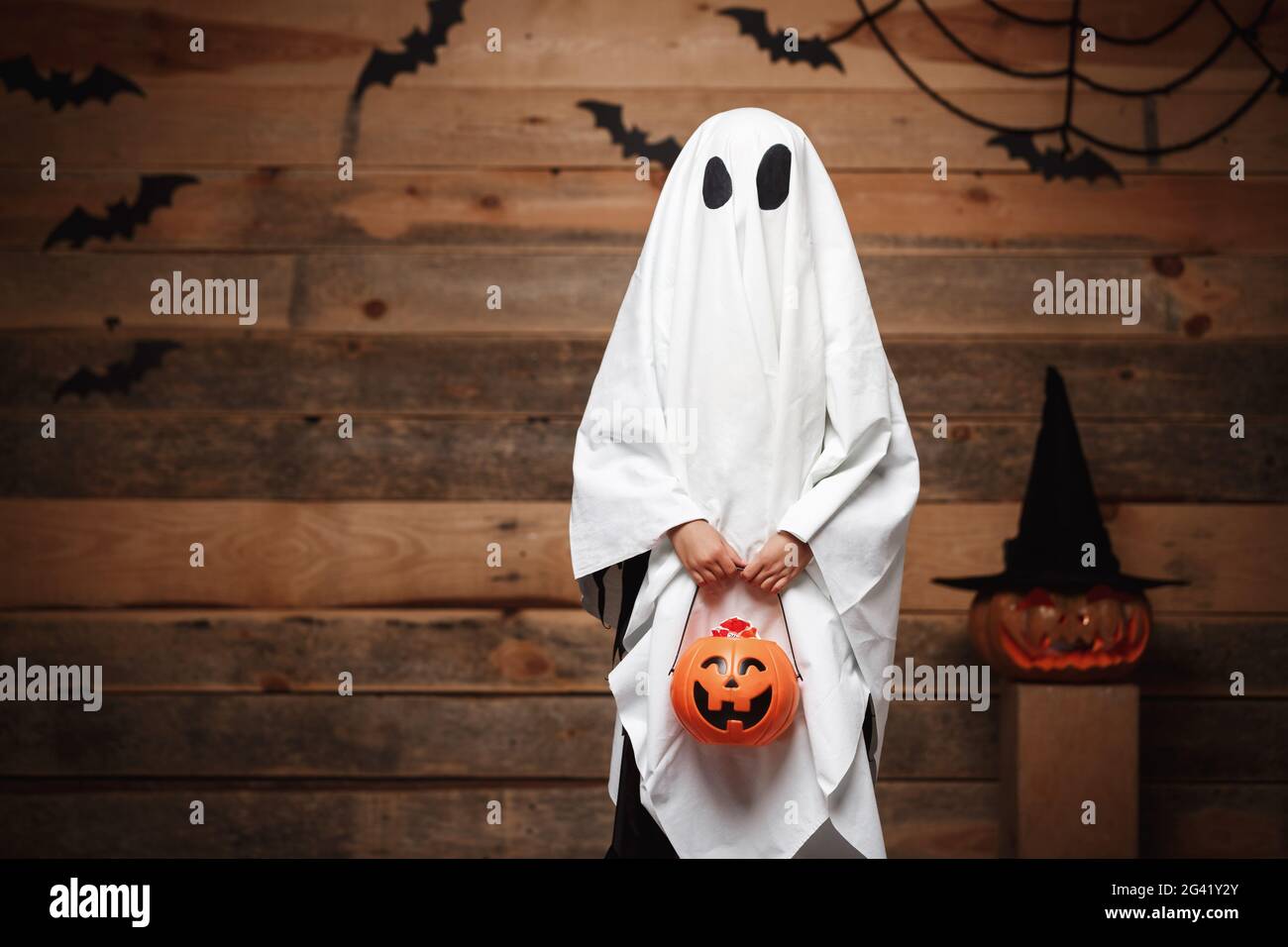 Halloween Concept - little white ghost with halloween pumpkin candy jar ...
