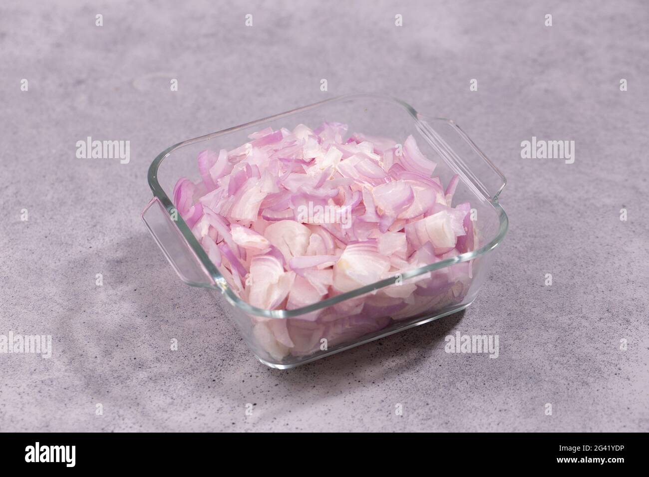 Chopped Onion arranged in a square glass bowl with cement grey ...