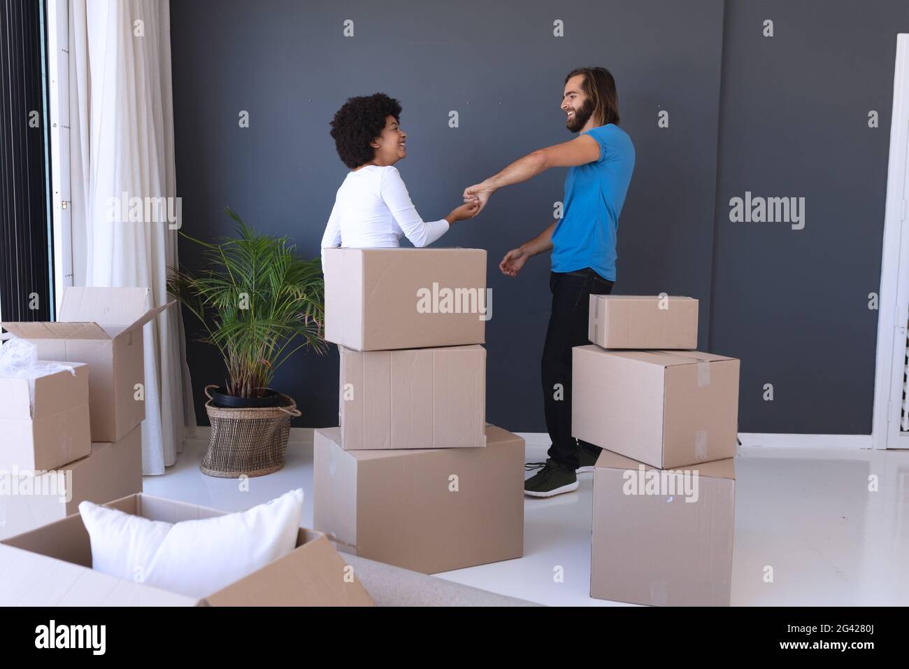 Happy diverse couple moving house smiling and dancing Stock Photo - Alamy