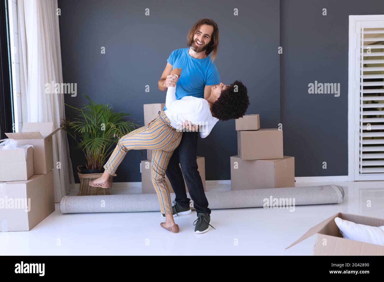 Happy diverse couple moving house smiling and dancing Stock Photo - Alamy