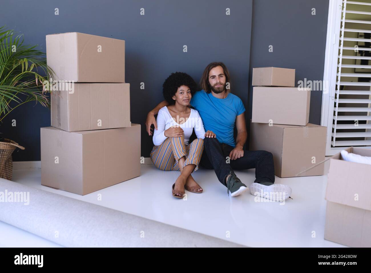 Happy diverse couple moving house sitting and embracing Stock Photo - Alamy