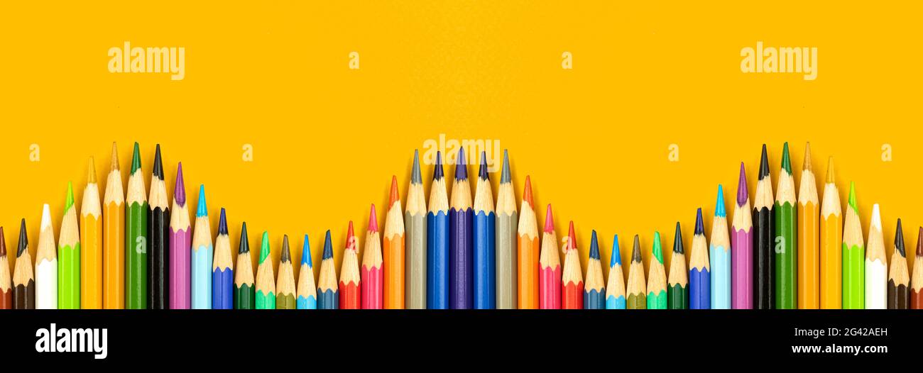 School banner with wavy color pencils border on a yellow table ...
