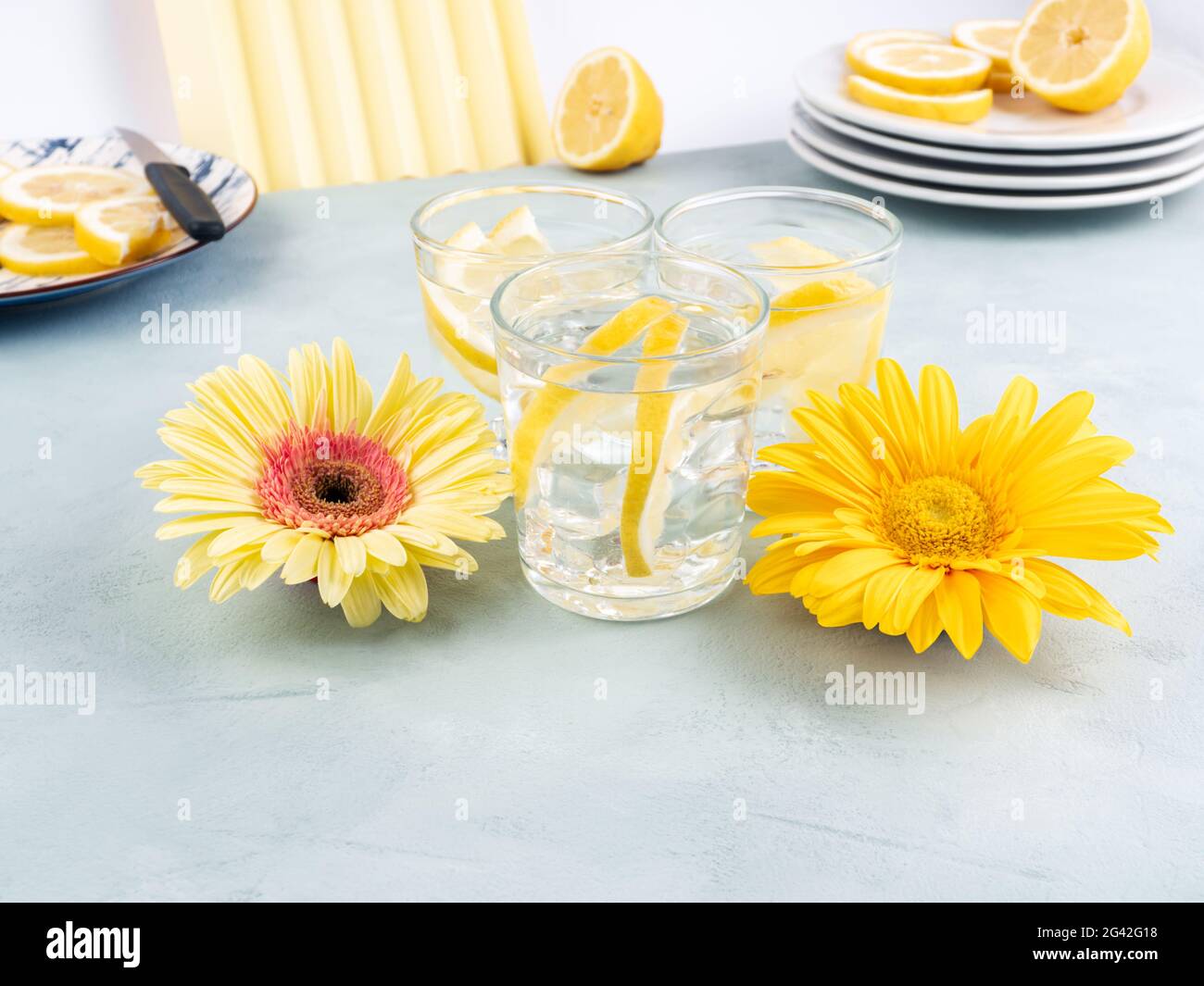 Lemon water drink with ice cubes on stone background with gerbera daisy ...
