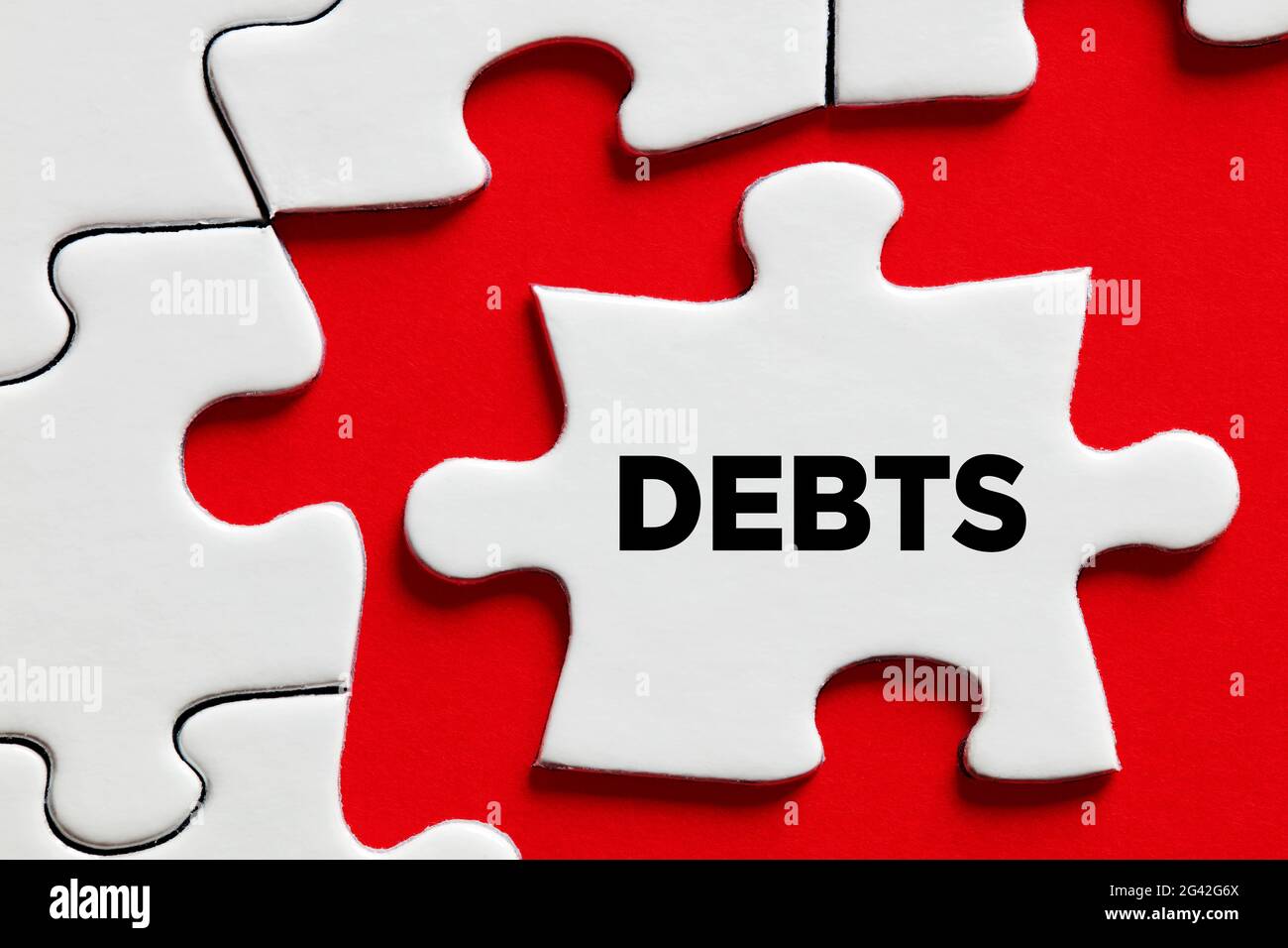 The word debts on a puzzle piece with red background. Financial debt ...