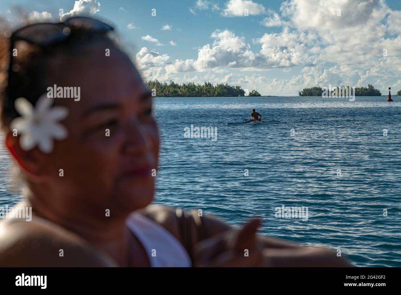 Outrigger canoe in the Bora Bora lagoon with woman in foreground ...