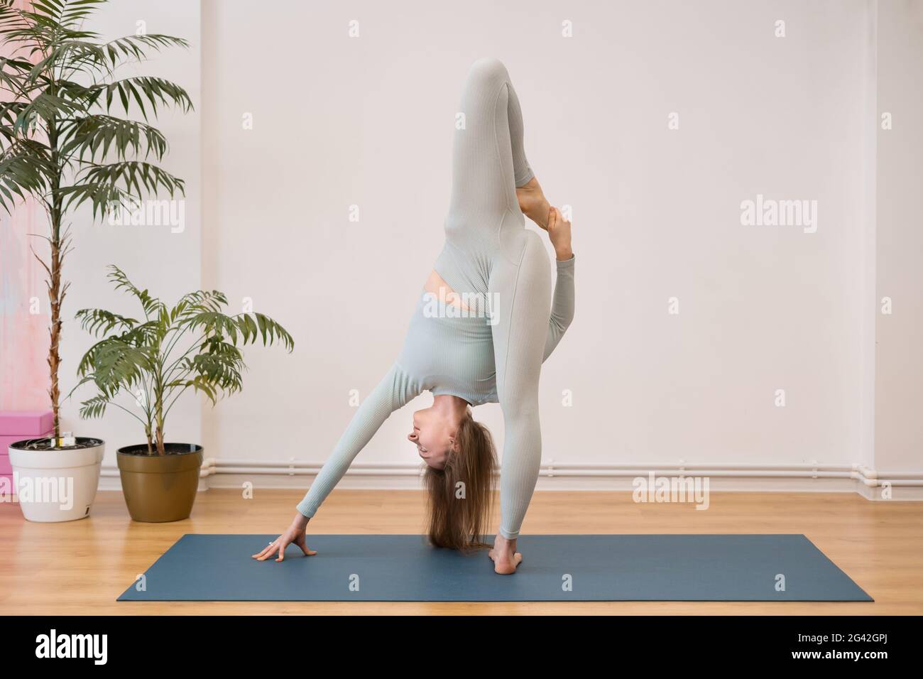 Sporty young woman doing yoga practice on white wall background with ...