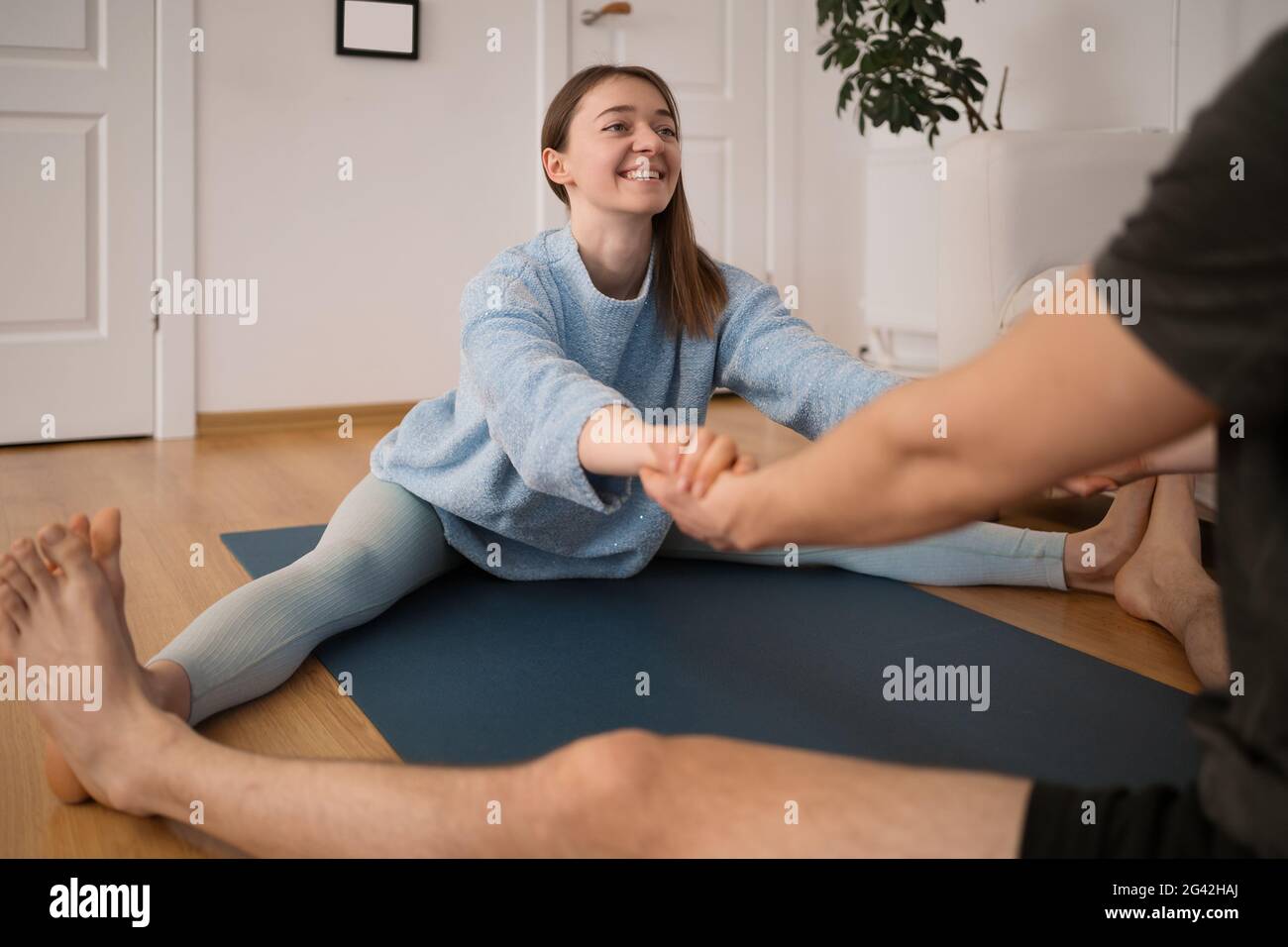 Sporty millennial couple stretching after training on mats on floor ...