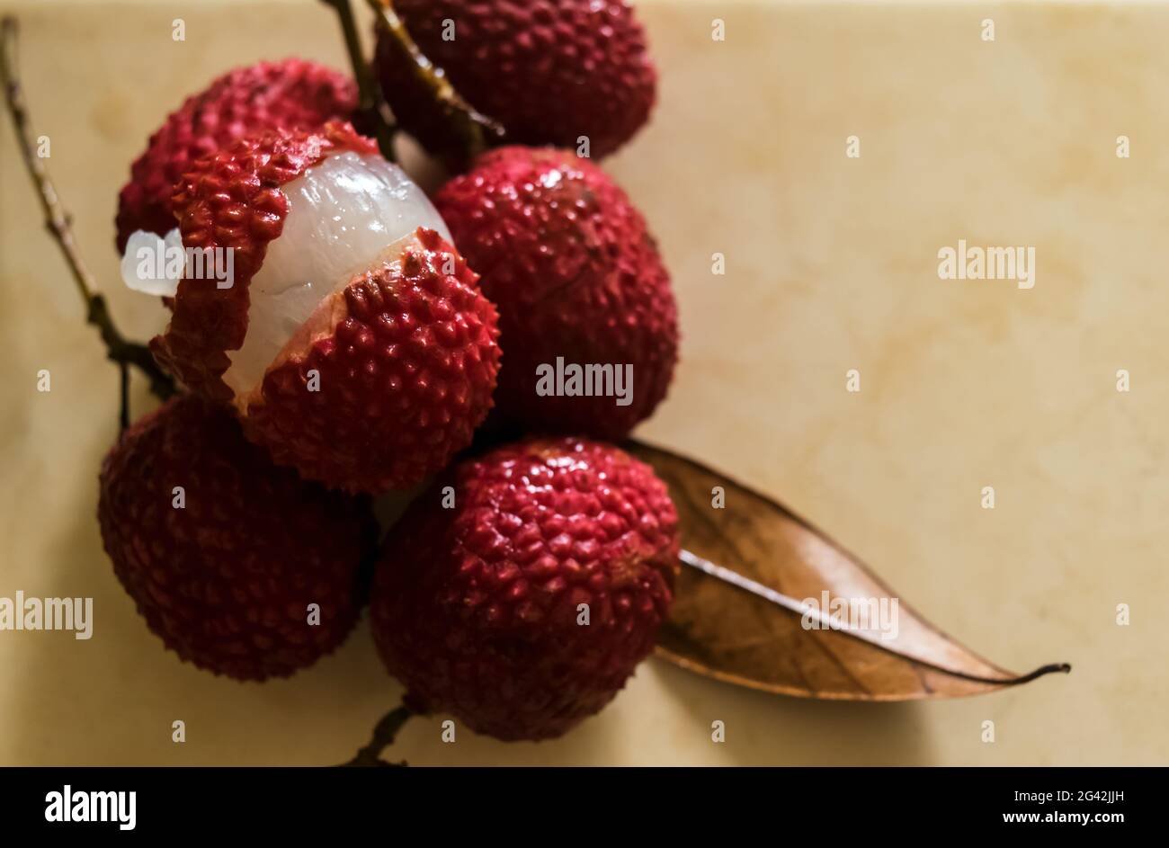 Close up of a small bunch of ripe lychee fruits on a light brown ...