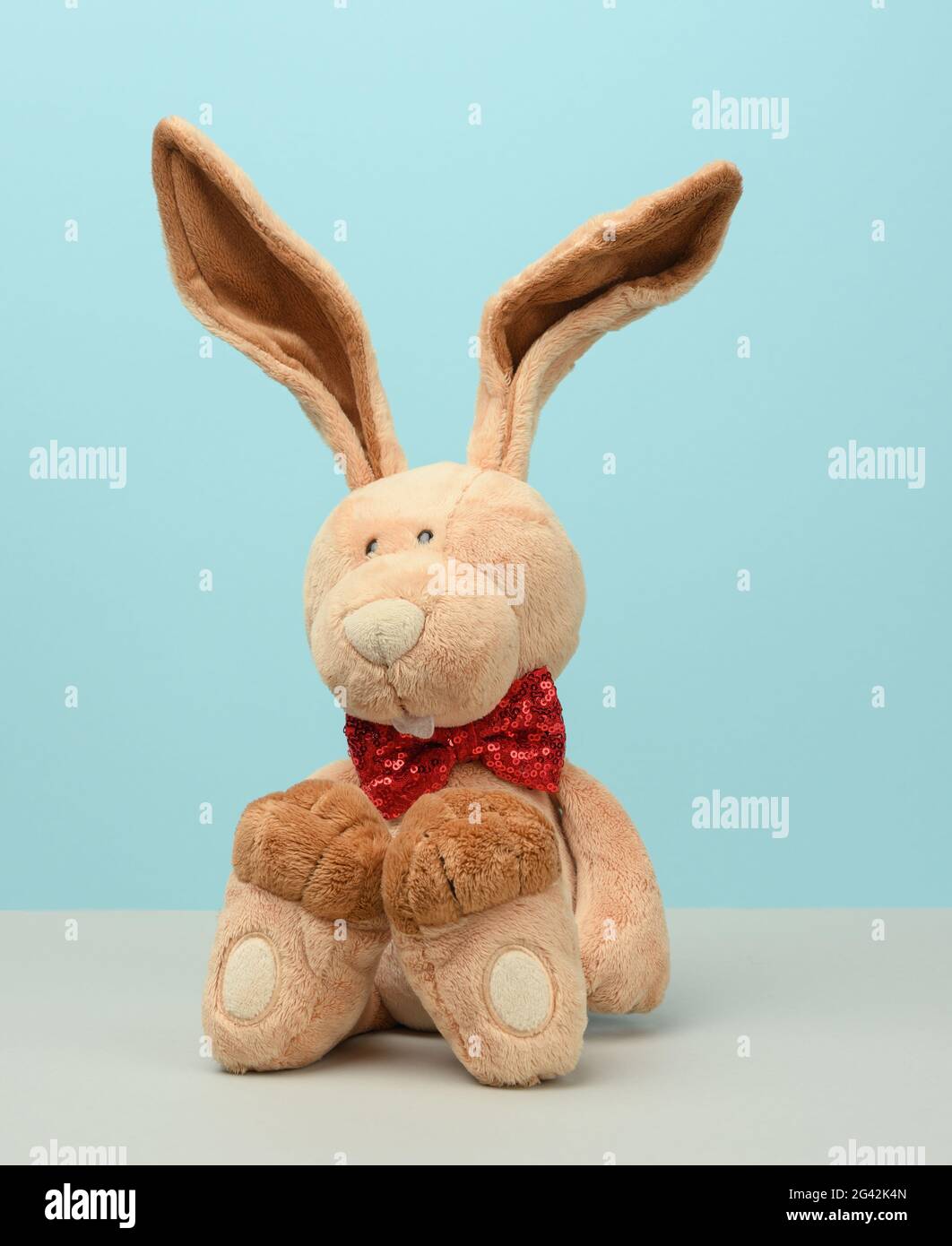 Cute plush hare with long ears, a red butterfly tied around the neck ...