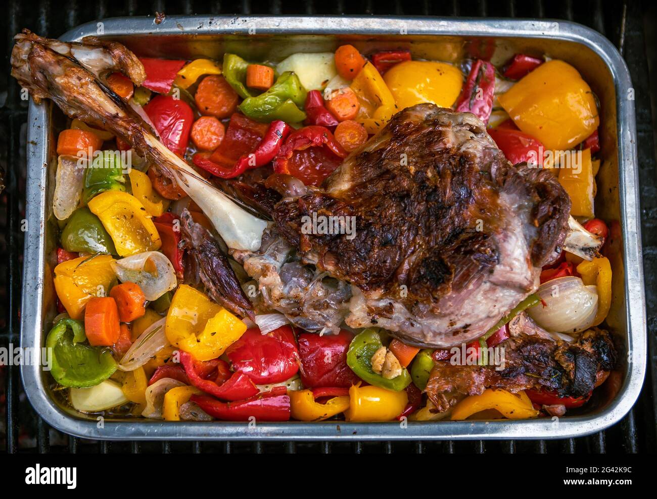 Chef cooking a delicious leg of lamb on a barbecue with colors peppers ...