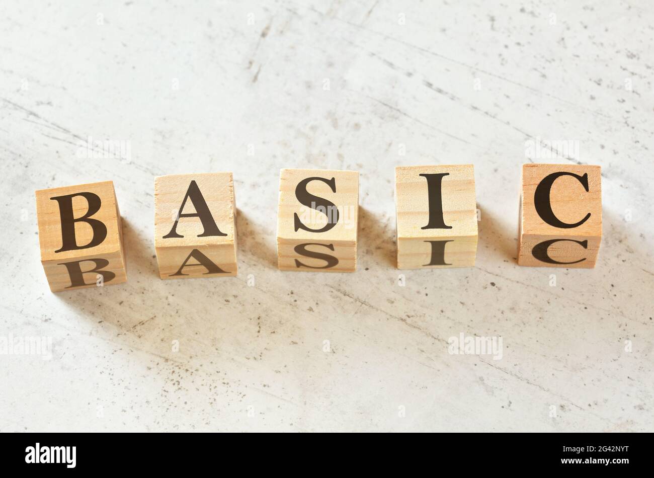 Five wooden cubes with word BASIC on white stone like board, view from ...