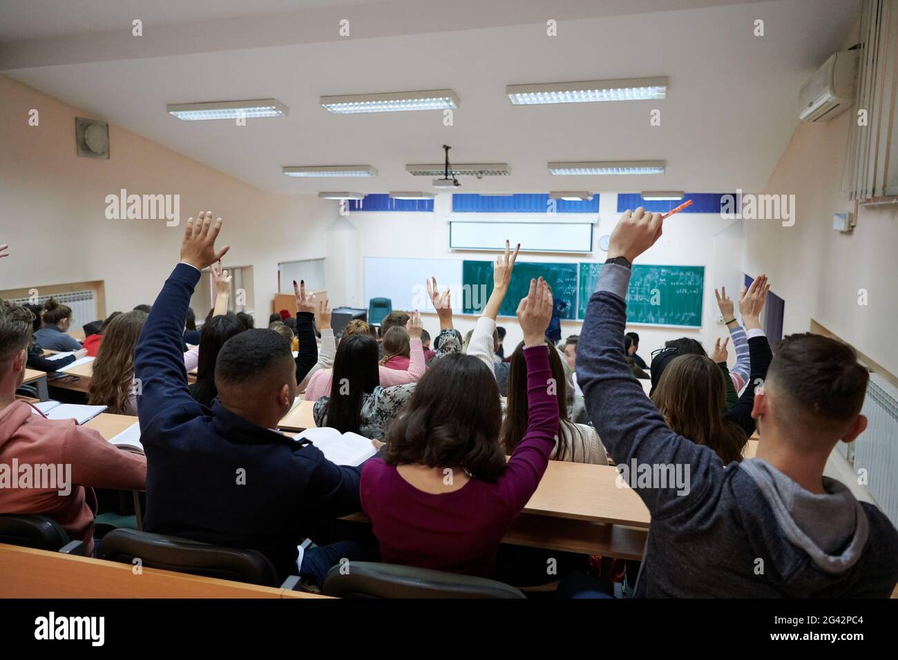 Raised hands and arms of large group of people in class room Stock ...